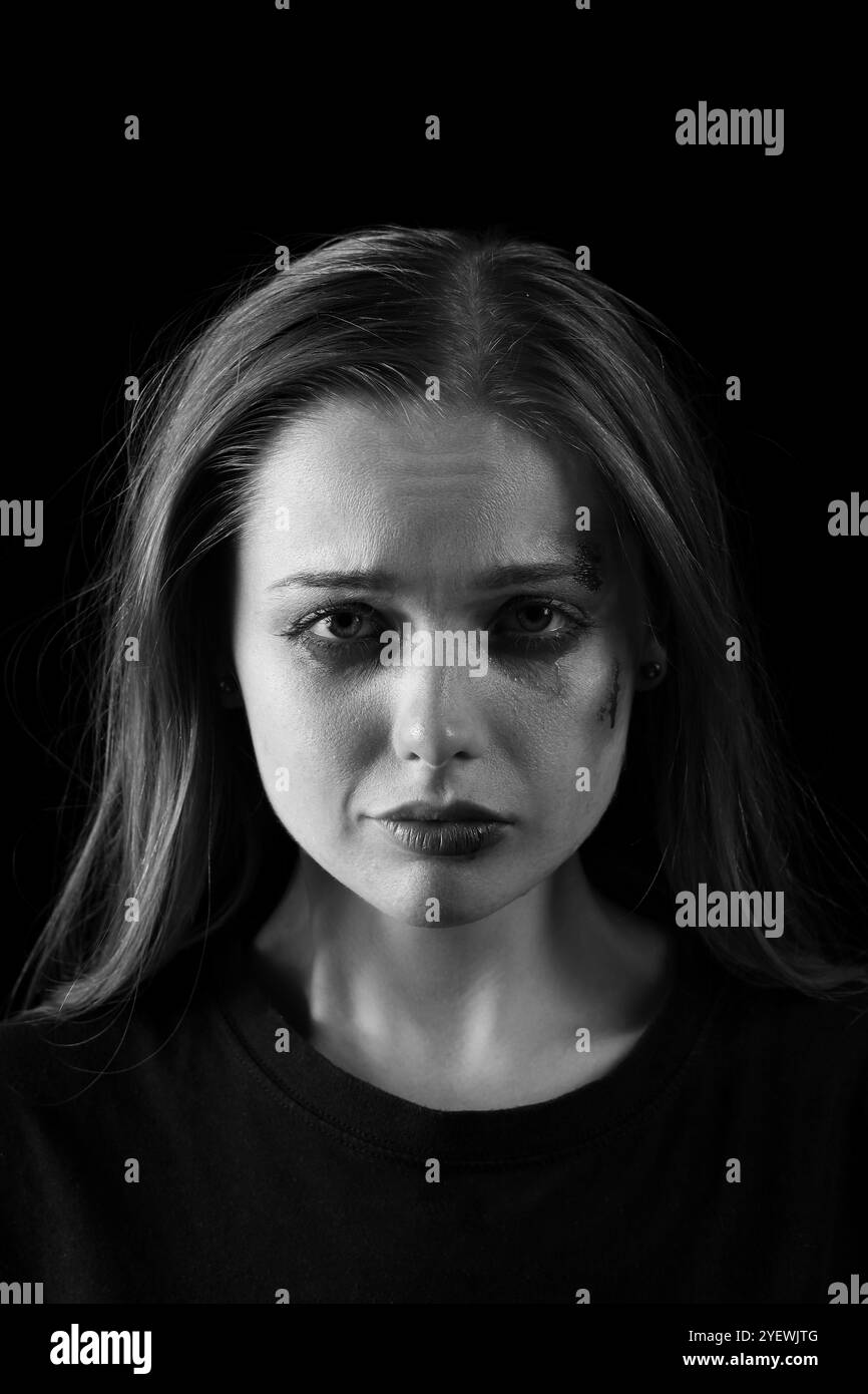 Black and white portrait of young crying bruised woman on dark ...
