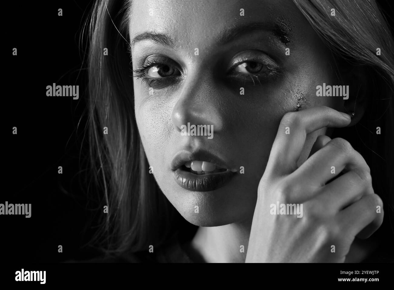 Black and white portrait of young crying bruised woman on dark ...