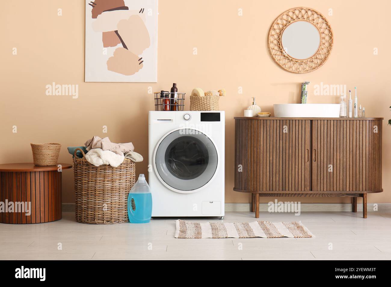 Modern washing machine, basket with laundry, chest of drawers and ...