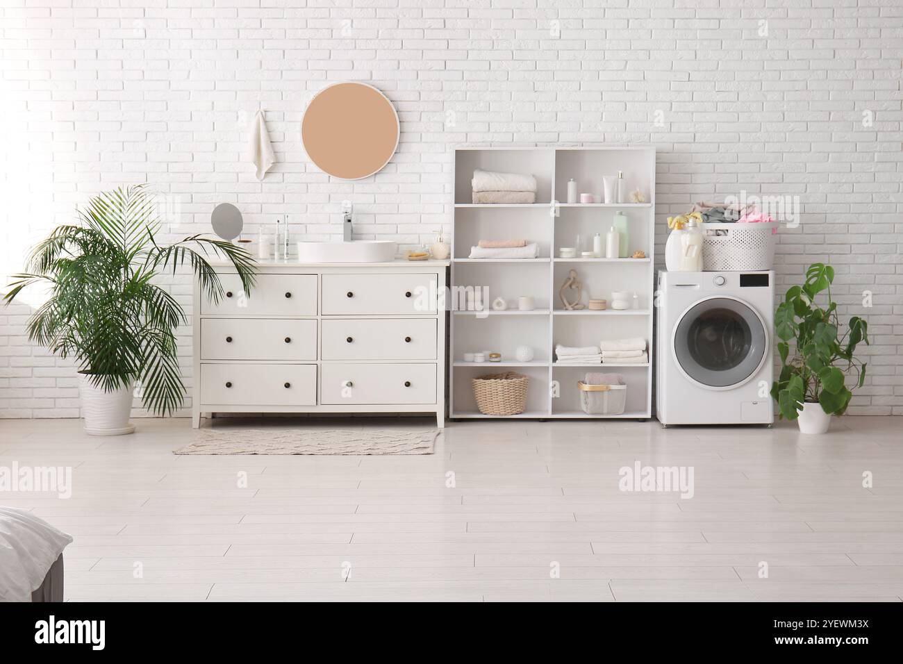 Modern washing machine, shelving unit and chest of drawers in interior ...