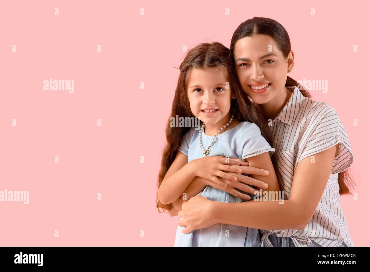 Embracing mother with her little daughter on pink background ...
