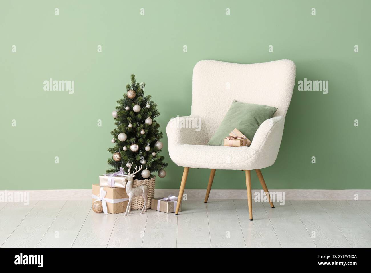 Armchair and Christmas tree with gifts near green wall in room Stock ...