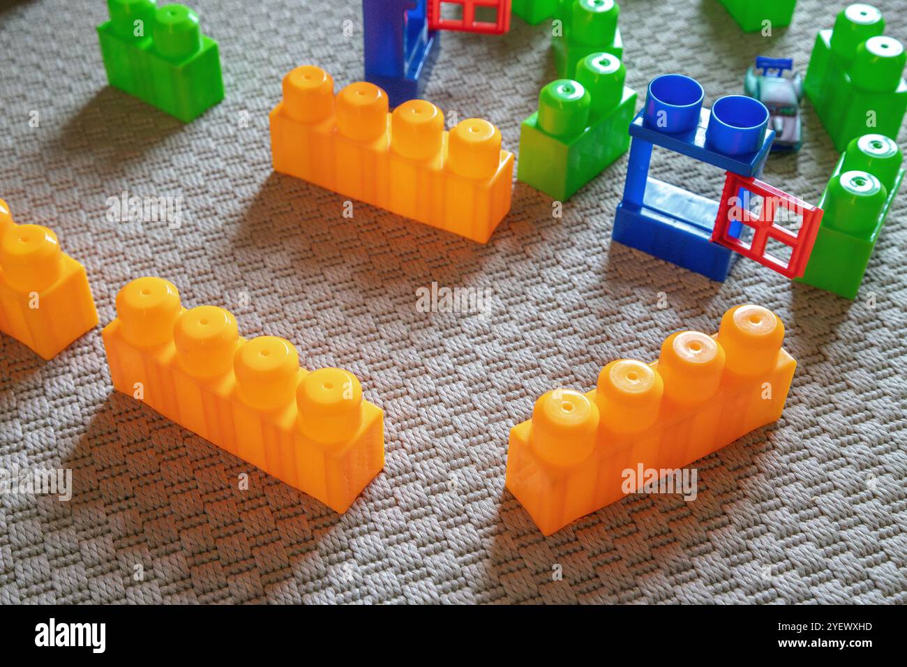 Colorful plastic building blocks arranged on a carpet, creating a ...