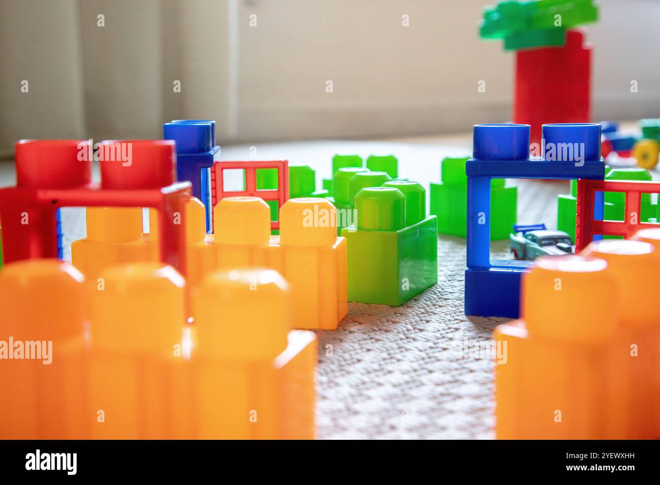 Colorful plastic building blocks arranged on a carpet, creating a ...