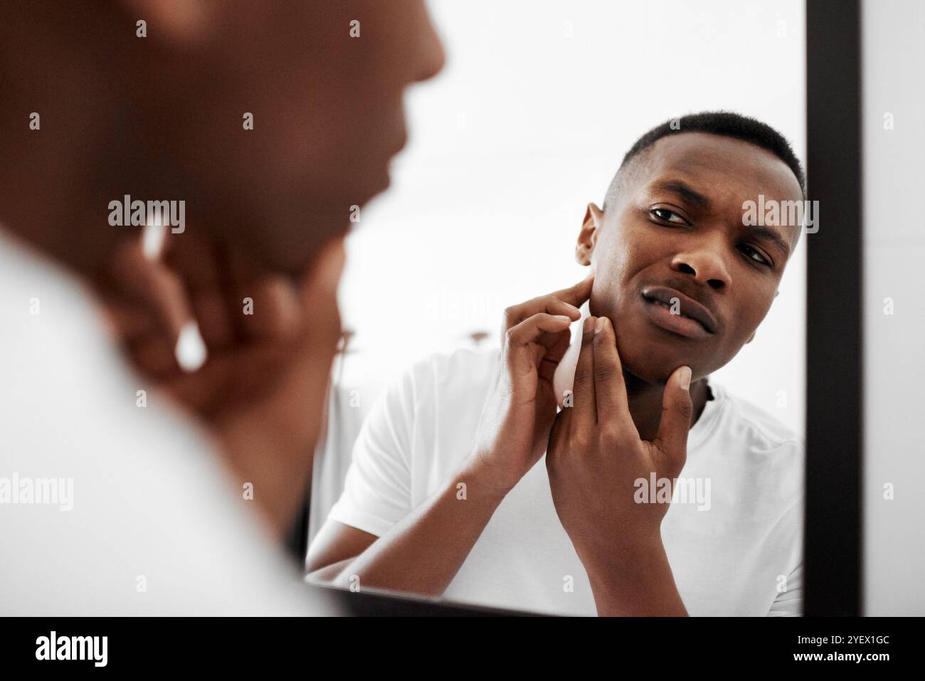 Black man, skincare and touch in bathroom with mirror, pimple or acne ...
