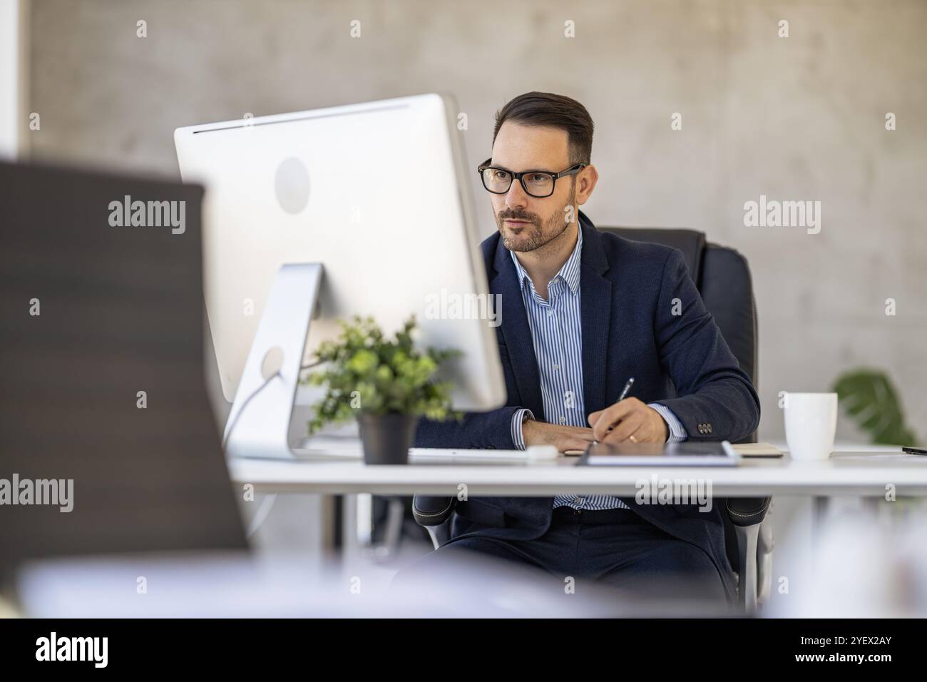 A professional businessman intently works at his computer in a sleek ...