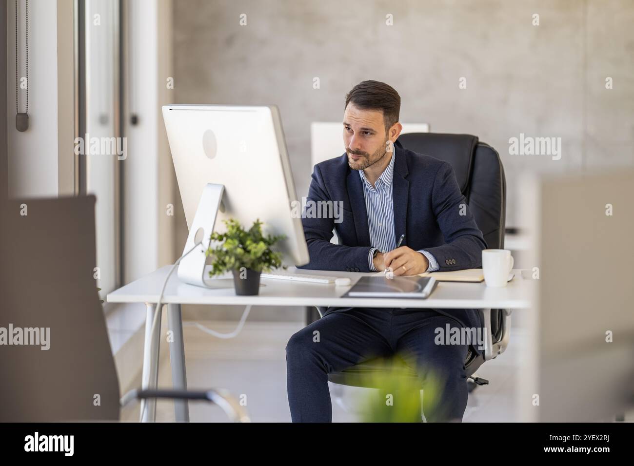 A business professional in a suit focuses intently on his computer ...