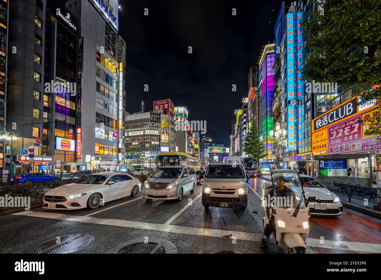 Traffic on busy street at night with brightly lit buildings in the ...