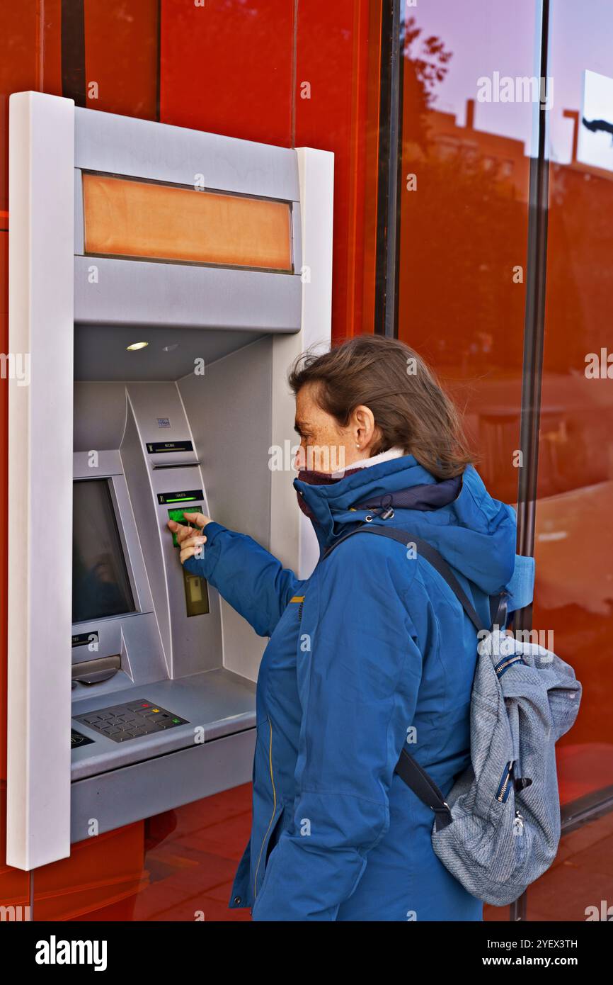 A woman is using a card reader to pay for something. She is wearing a ...
