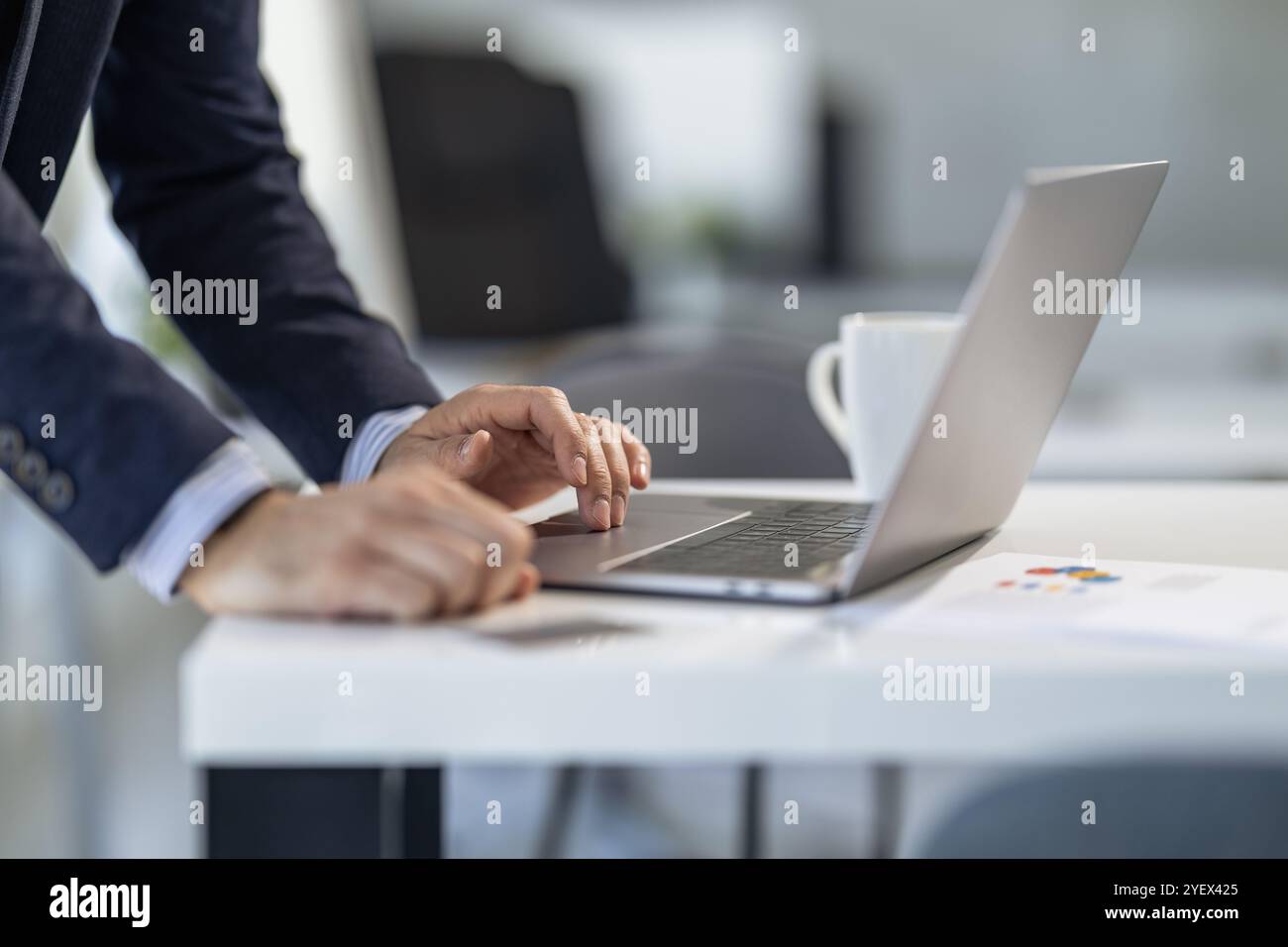 A business professional in a suit working on a laptop, representing ...