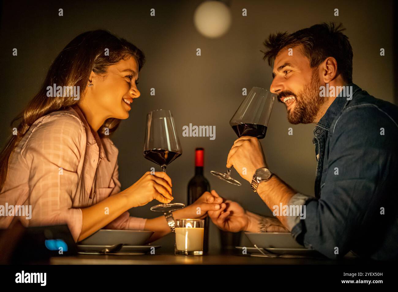 A couple enjoys a romantic dinner with wine and candlelight, creating ...