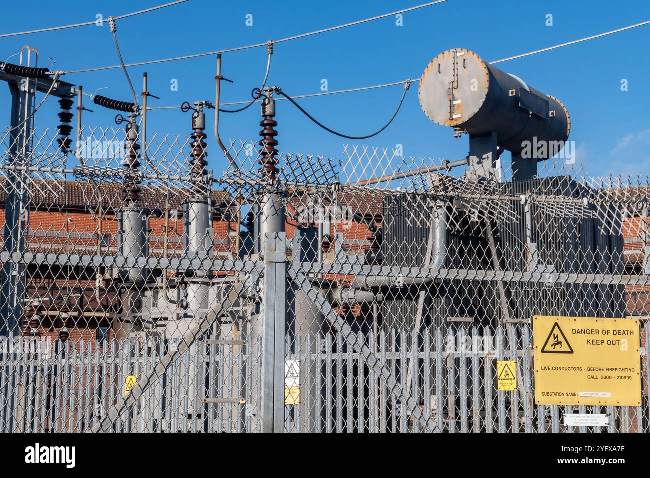 an electricity substation with barbed wire fence and yellow danger of ...