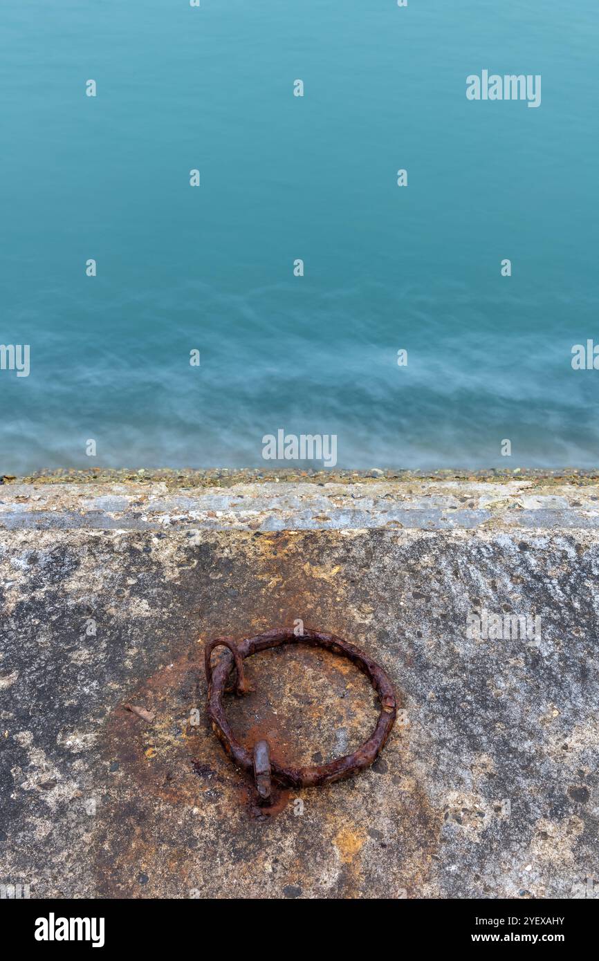 Mooring ring rusting or corroded on a sea wall with sea in background ...