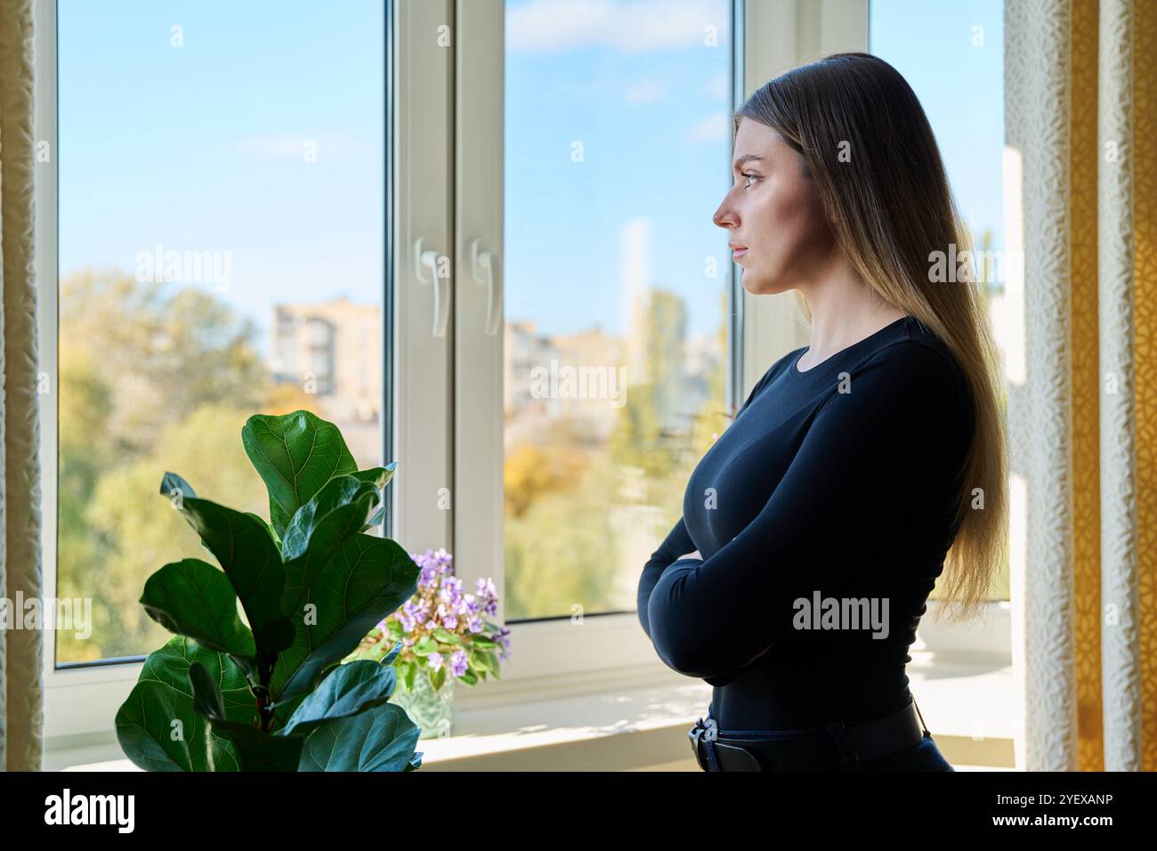 Serious young woman looking out the window Stock Photo - Alamy