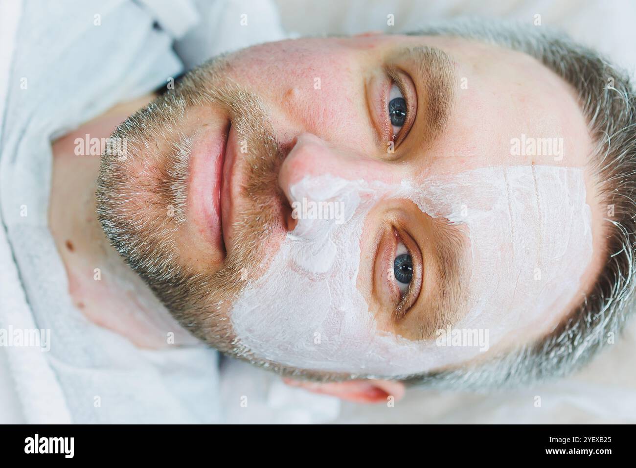 A cosmetologist cleans the skin of a man's face. A man does facial ...