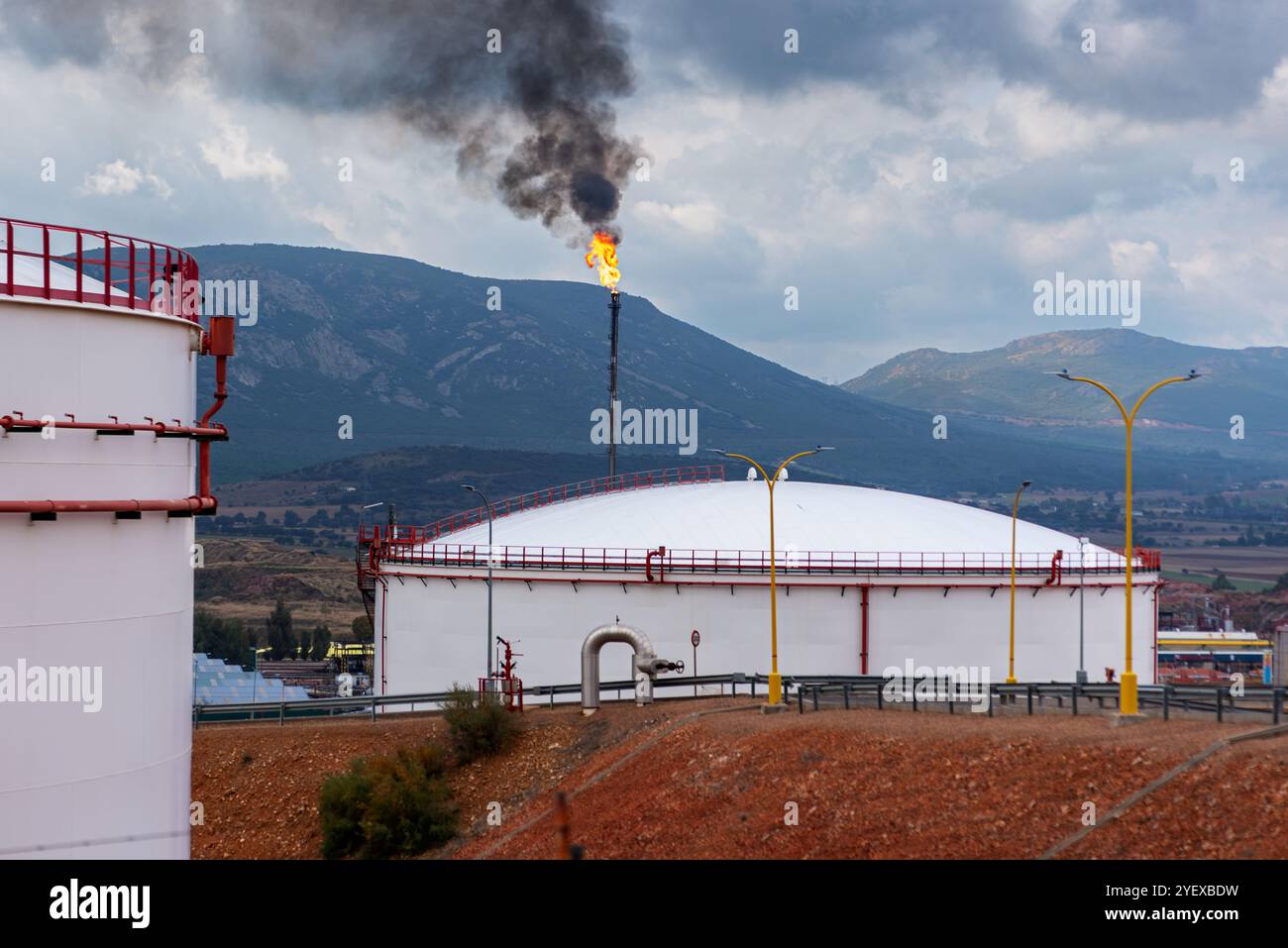 Oil tanks at a refinery with a chimney with a flare in the background ...