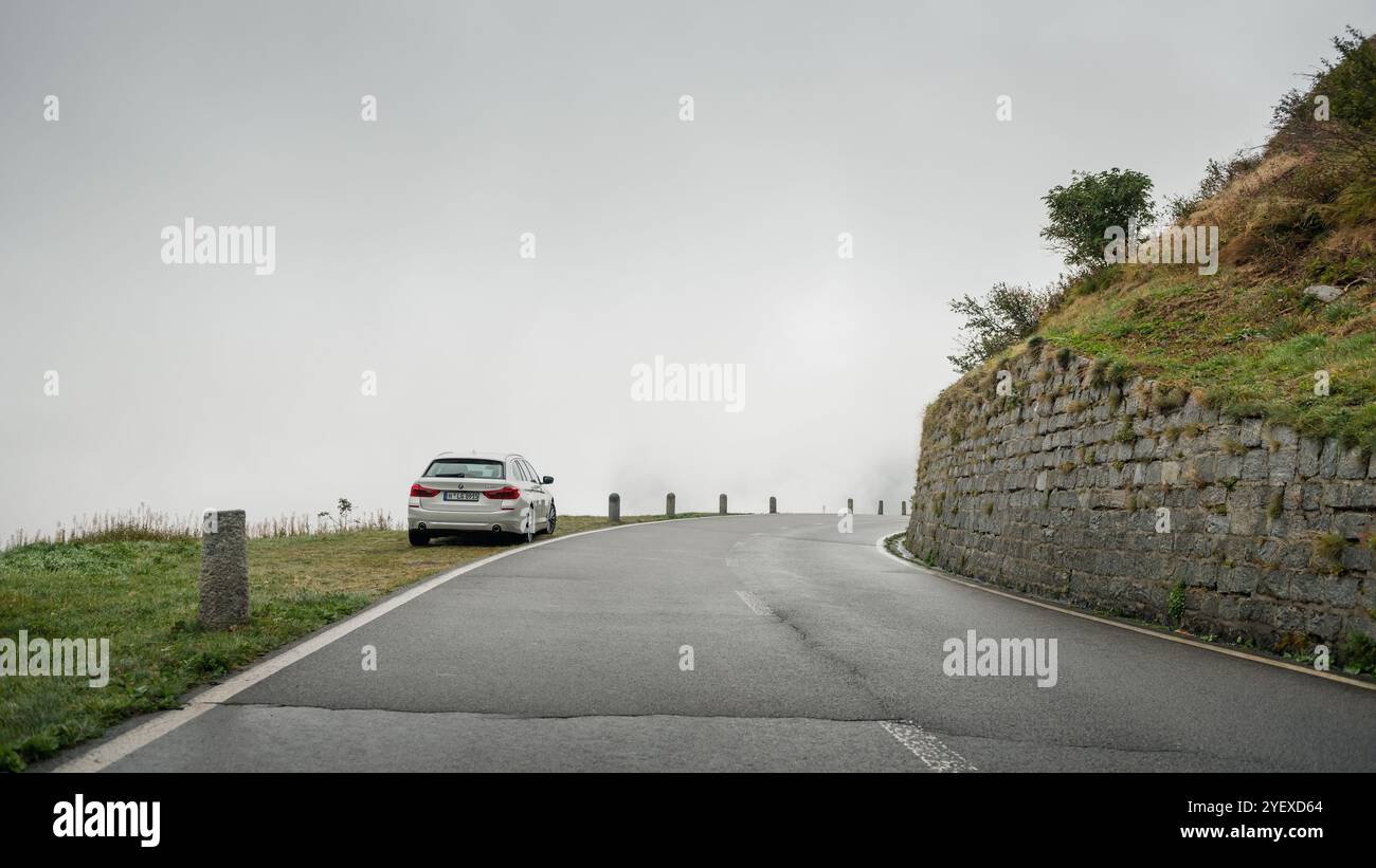 White BMW 5-series parked on a side of mountain pass in Swiss alps ...
