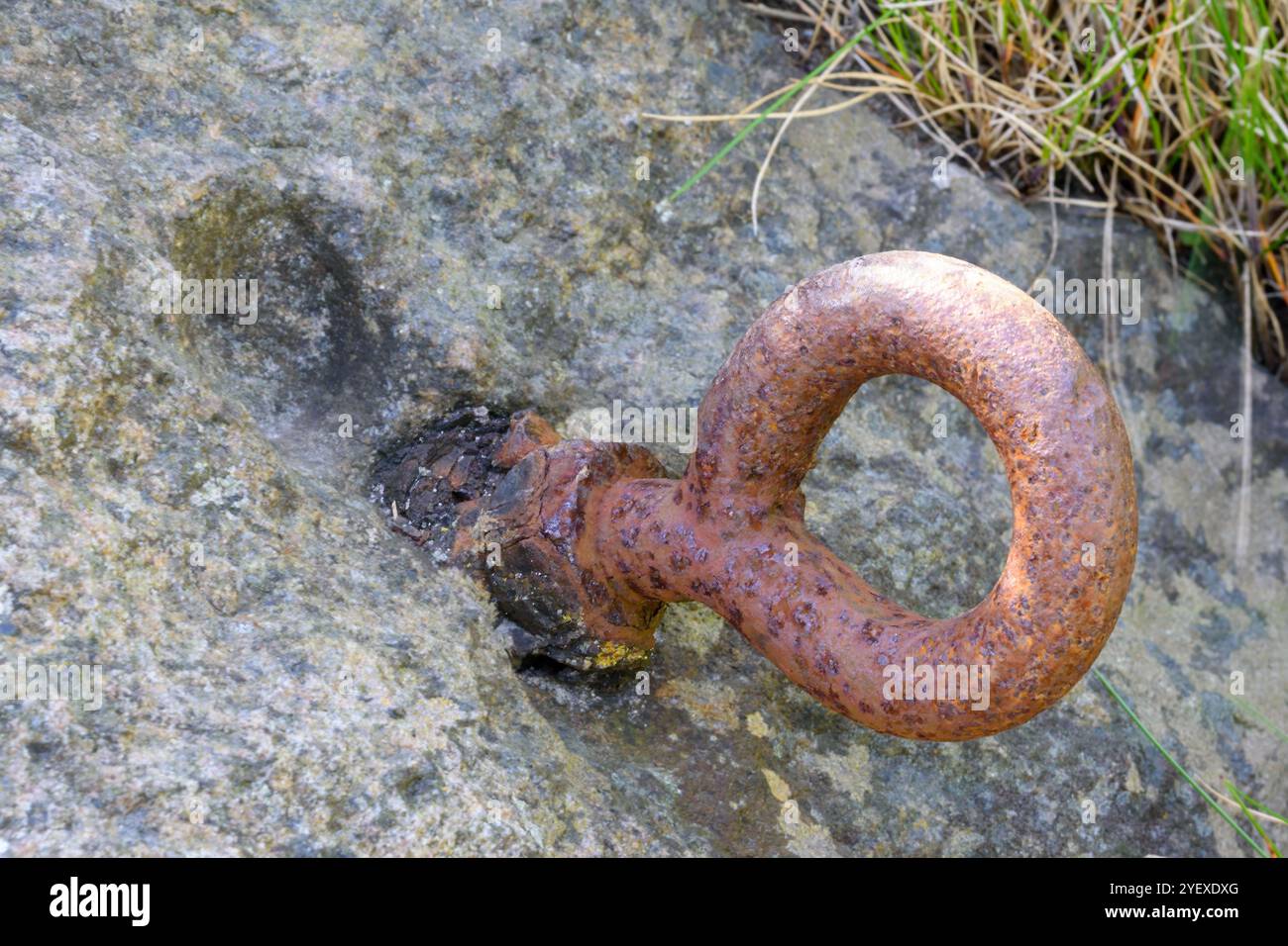 A rusty iron ring is set in a rocky surface, showing signs of age and ...
