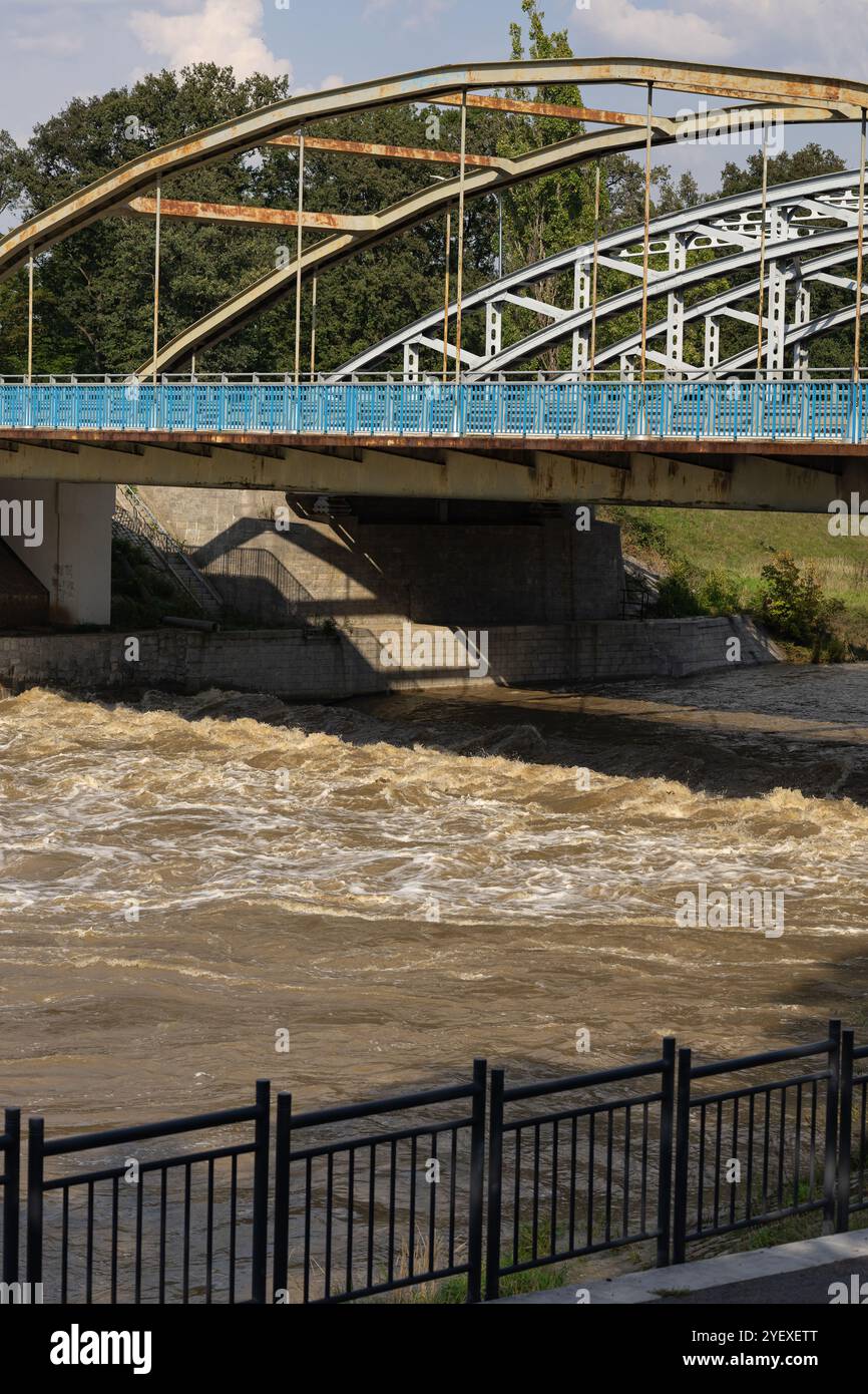 Rushing water flowing under a steel bridge after heavy rainfall ...
