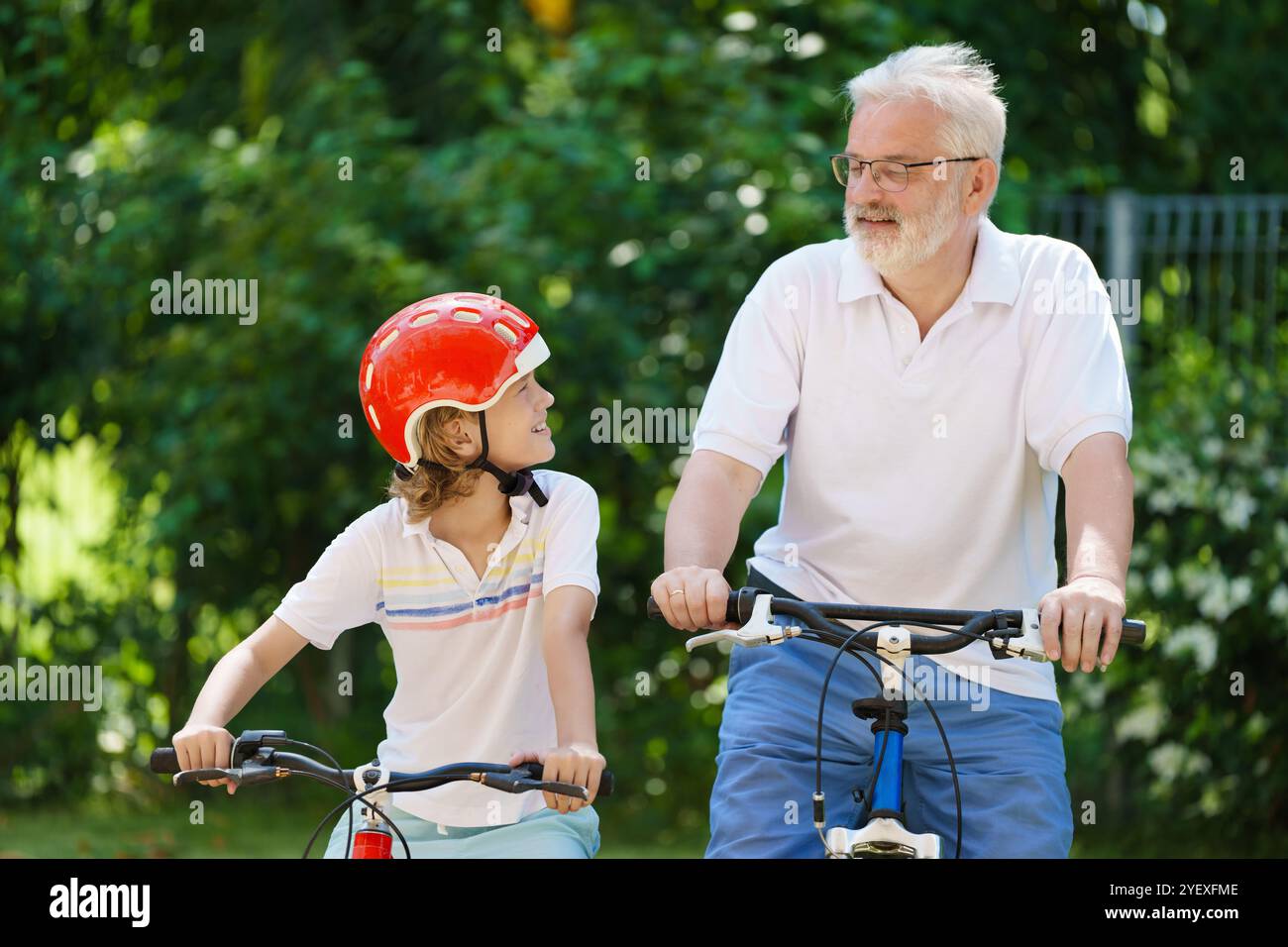 Grandfather and kids in sunny garden. Happy family riding bike in ...