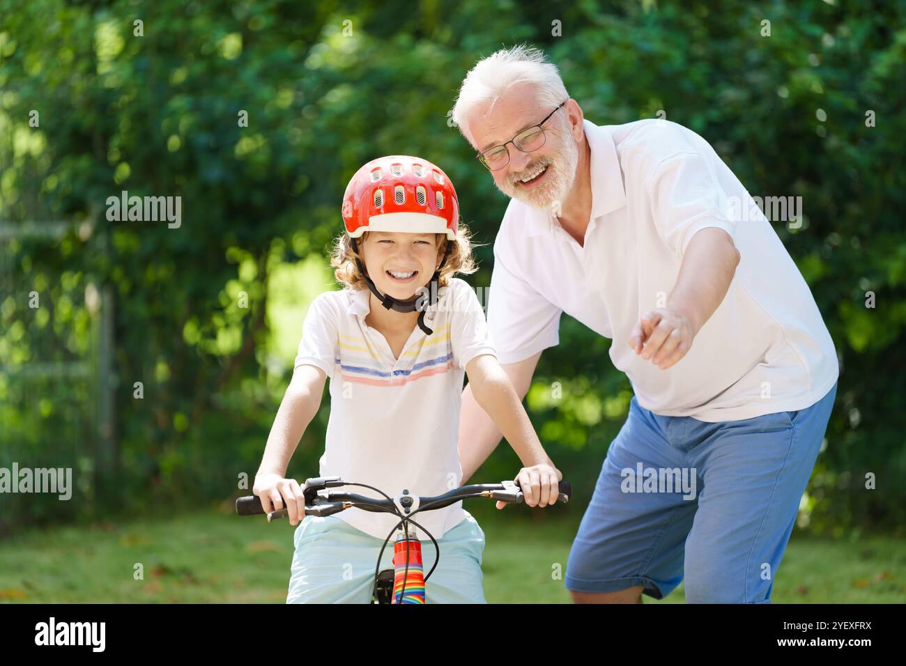 Grandfather and kids in sunny garden. Happy family riding bike in ...