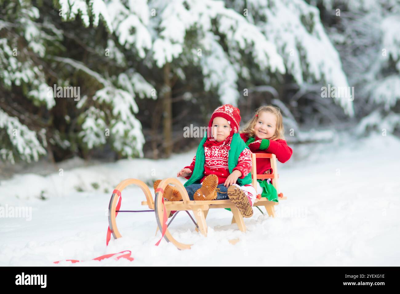 Kids on sleigh in winter forest. Merry Christmas greeting with little ...