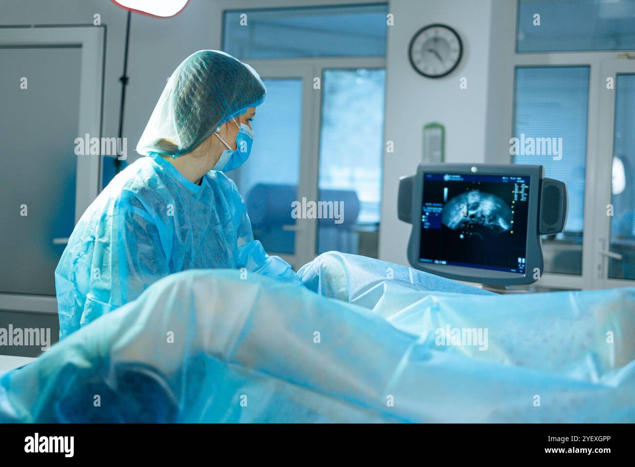 A female doctor performs an operation in a sterile operating room ...