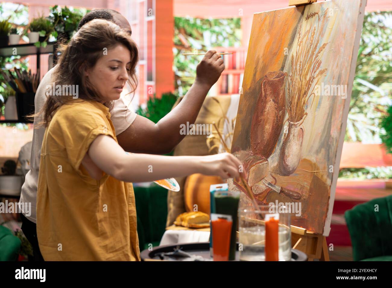 Talented artist and her apprentice applying watercolor paint on canvas ...