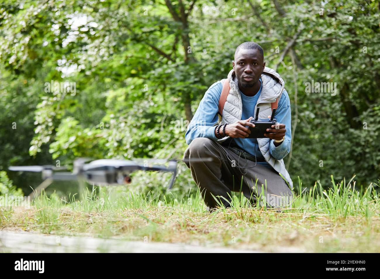 Full length portrait of young African American man flying drone in ...