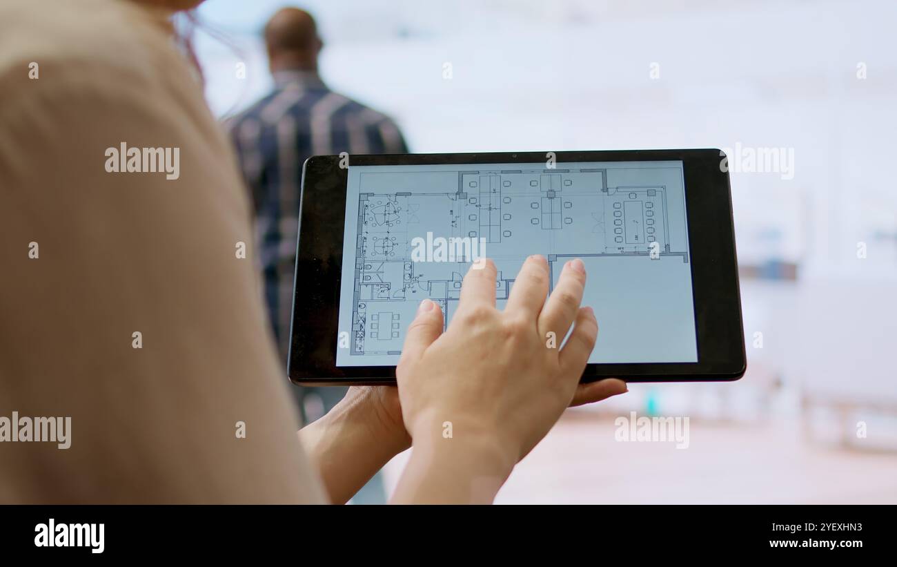 Real Estate Agent And Client Evaluating Blueprints And Discussing The