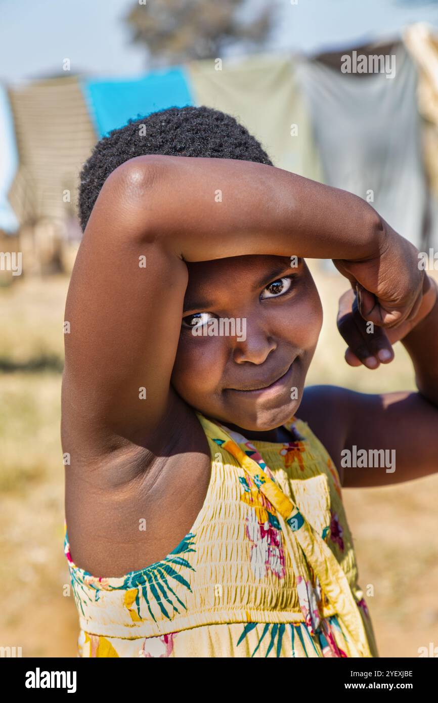 one village african child girl, standing in the yard washing line and ...