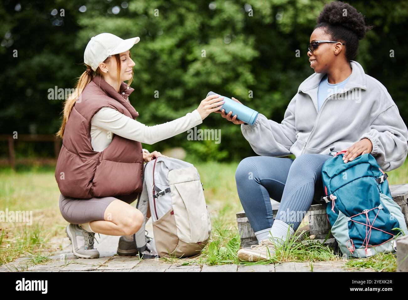 Side view portrait of two women tourists sharing water bottle while ...