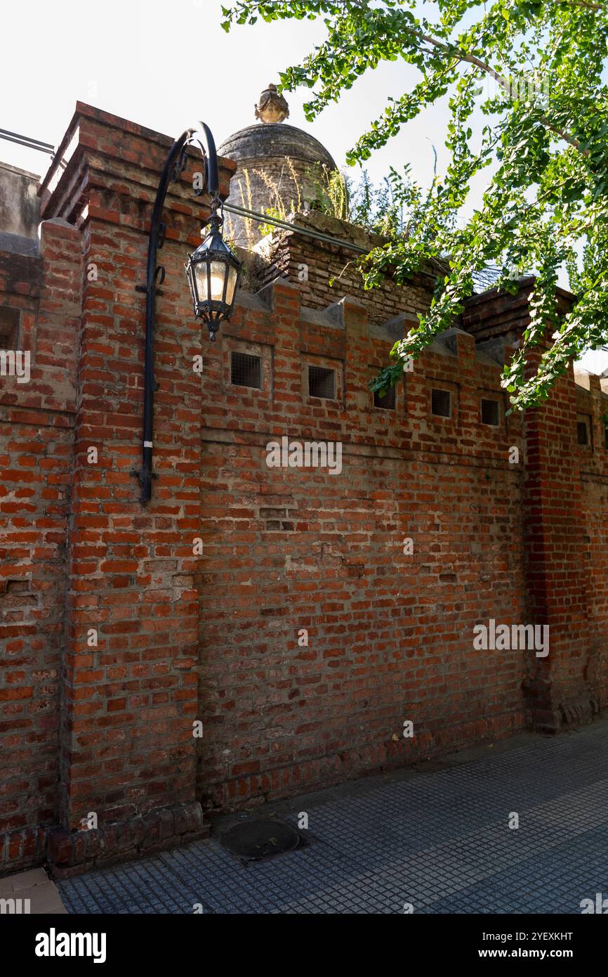 Ornate street lamp by the brick wall surrounding La Recoleta cemetery ...