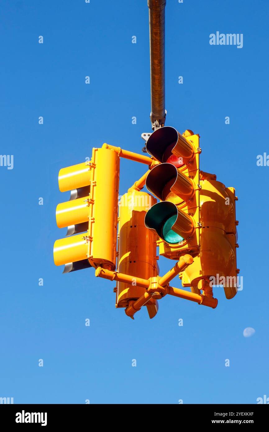 yellow traffic lights against bright blue sky hanging above 4 way ...