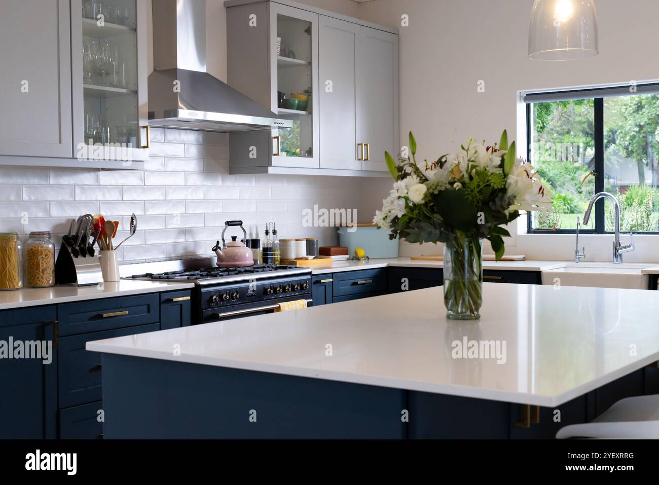 Modern kitchen with elegant white countertops and fresh flowers in vase ...