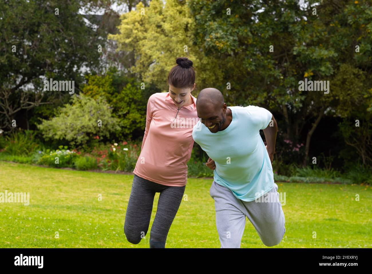 multiracial couple enjoying playful outdoor activity in lush green park ...