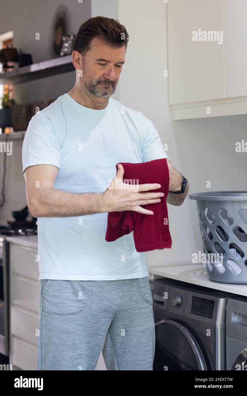 senior man folding laundry at home, focusing on household chores Stock ...