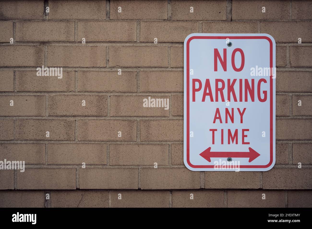No parking sign on the red brick wall clearly marking restricted area ...