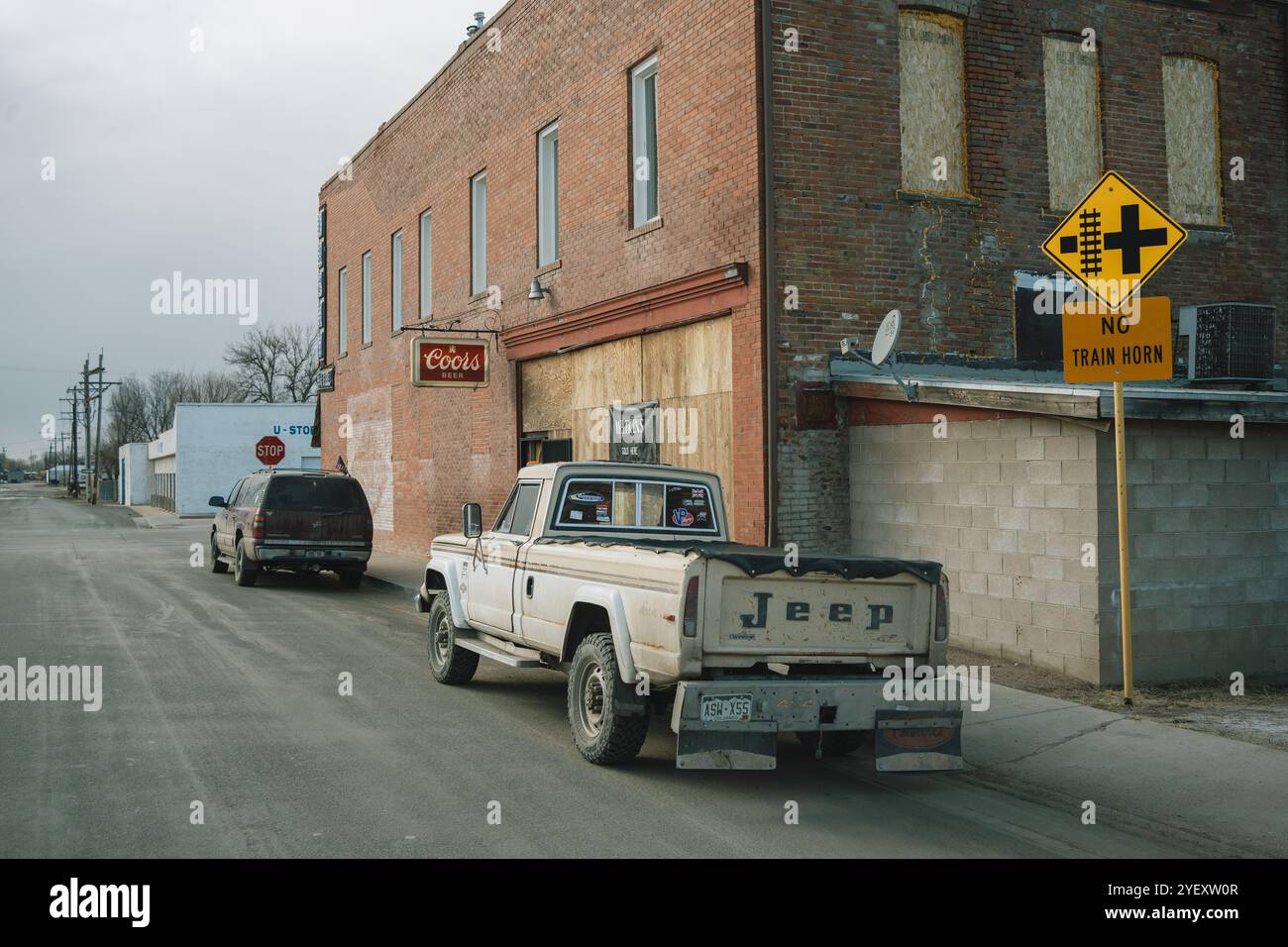 A vintage Jeep truck is parked on a quiet street next to a building ...