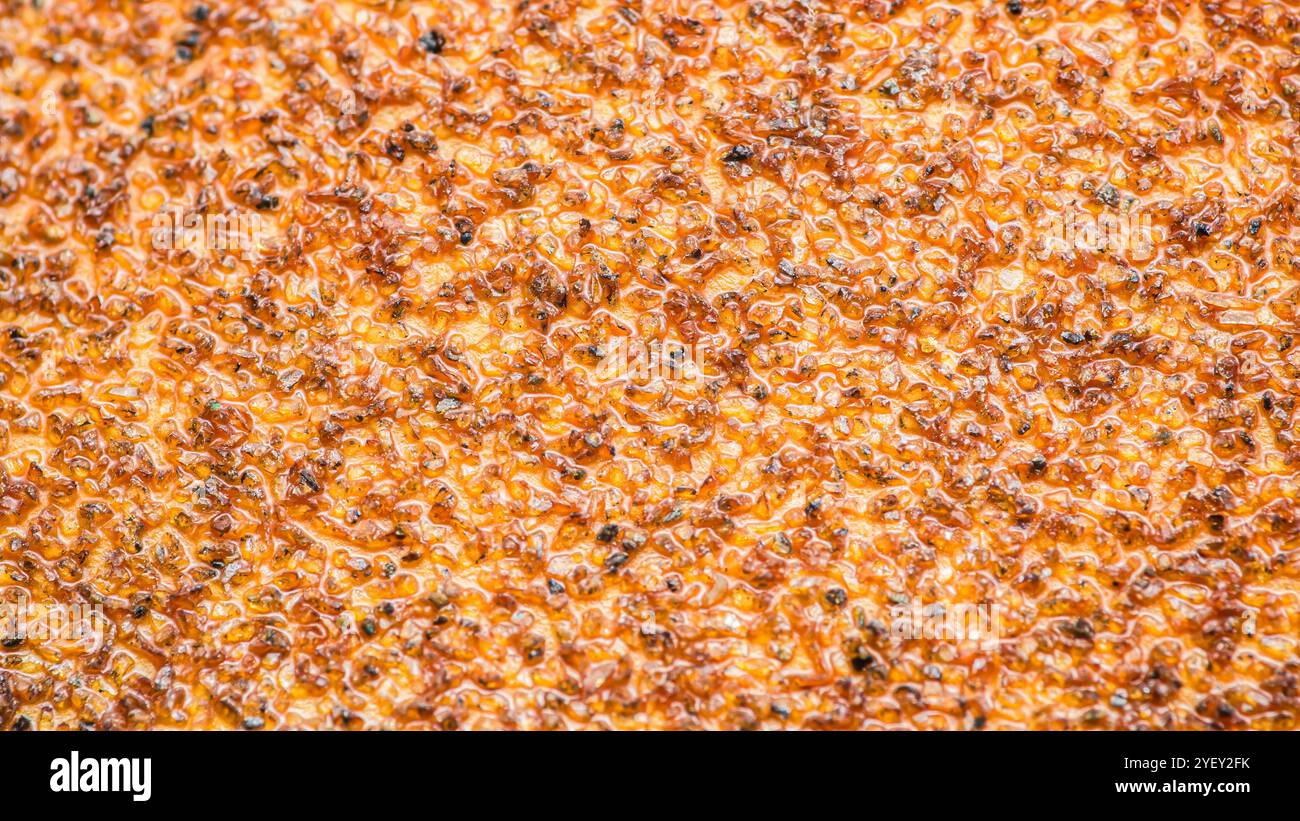 Extreme macro photograph of orange sandpaper grit, highlighting the ...