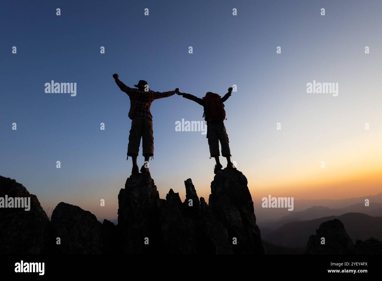 Silhouette of a team of climbers ascending a rugged mountain ...