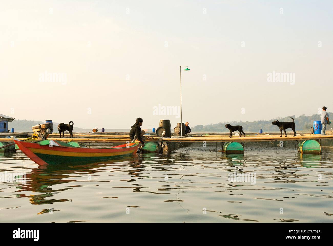 A man is sitting on a boat that is tied to the floating platform at the ...
