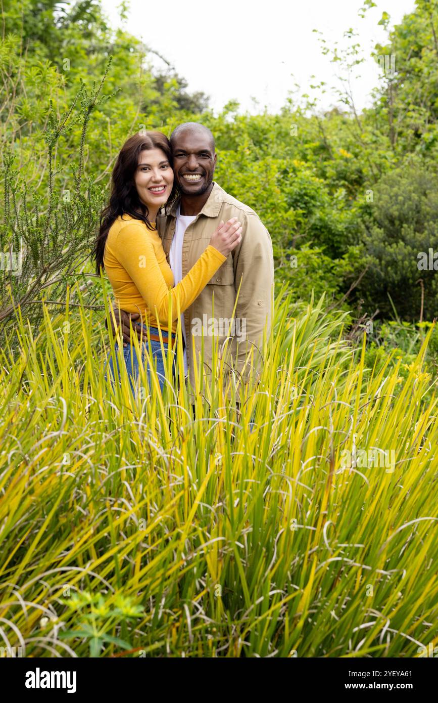multiracial couple embracing in lush garden, appreciating nature ...