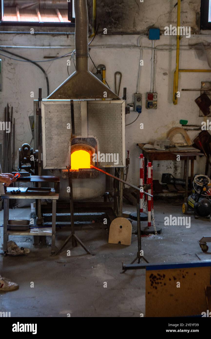 Murano glass-blowing factory. blower forming beautiful piece of glass ...