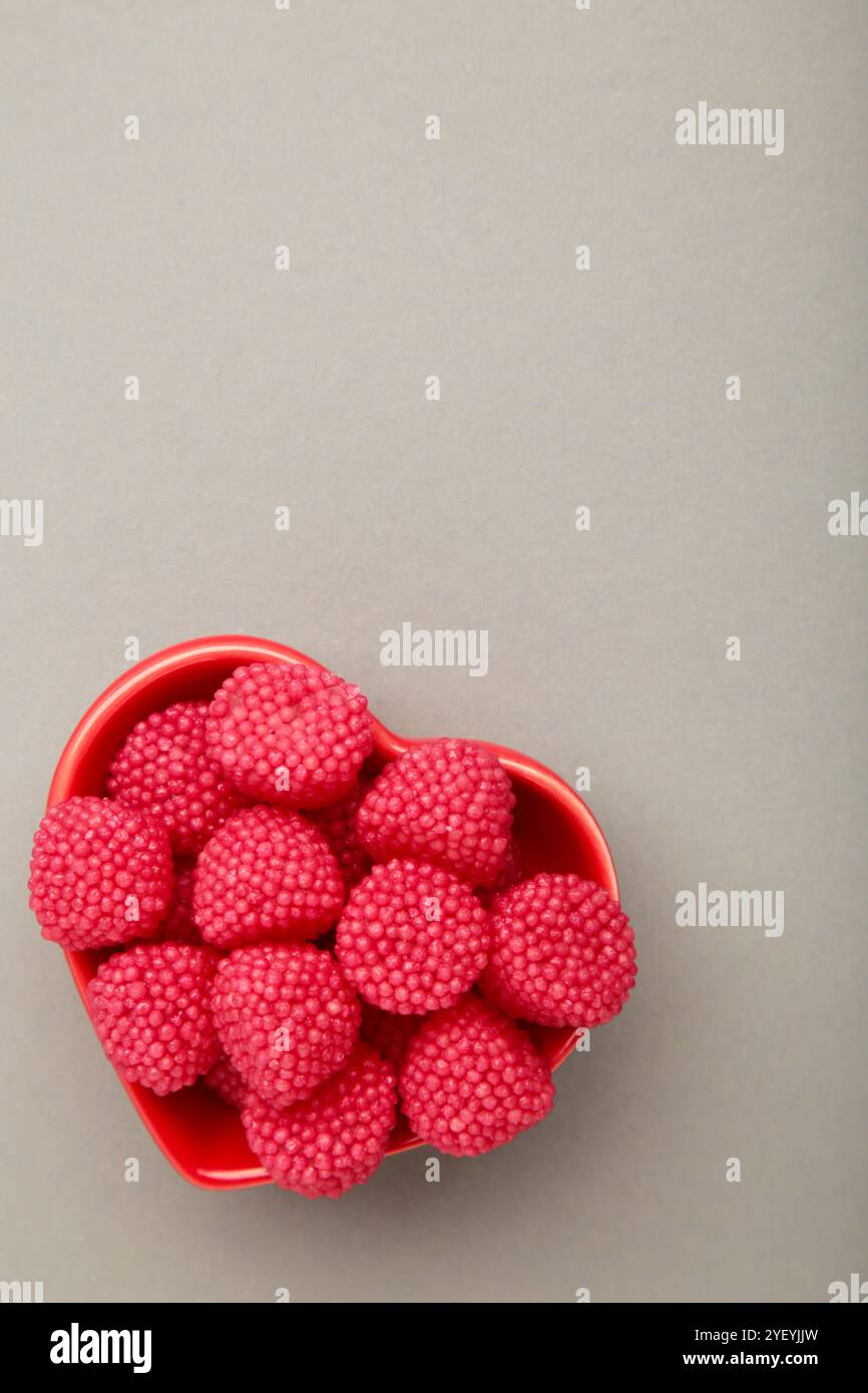 Raspberry and blackberry candy on bowl on grey background. Vertical ...