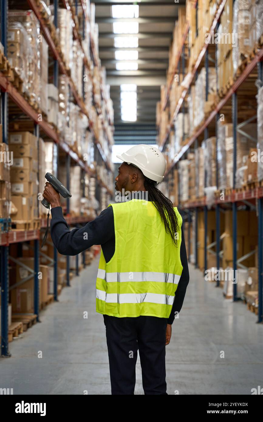 Logistics employee using handheld scanner on packages in warehouse ...
