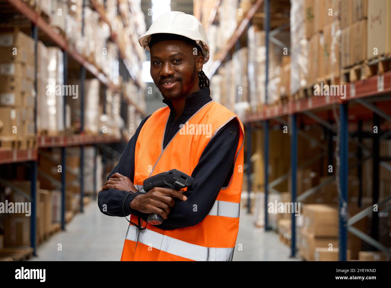 Smiling warehouse worker holding barcode scanner in logistics center ...