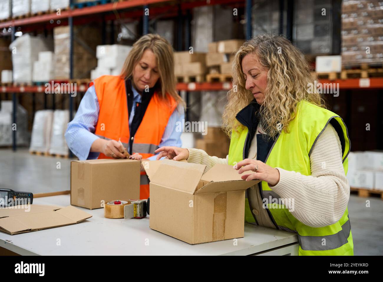 Warehouse staff members handling packages on packing table Stock Photo ...