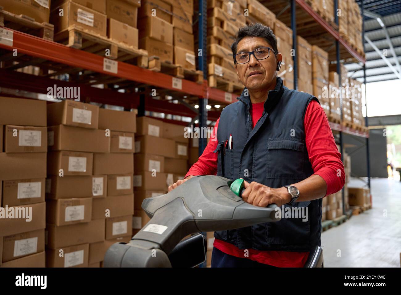 Latin american warehouse worker driving forklift arranging cardboard ...