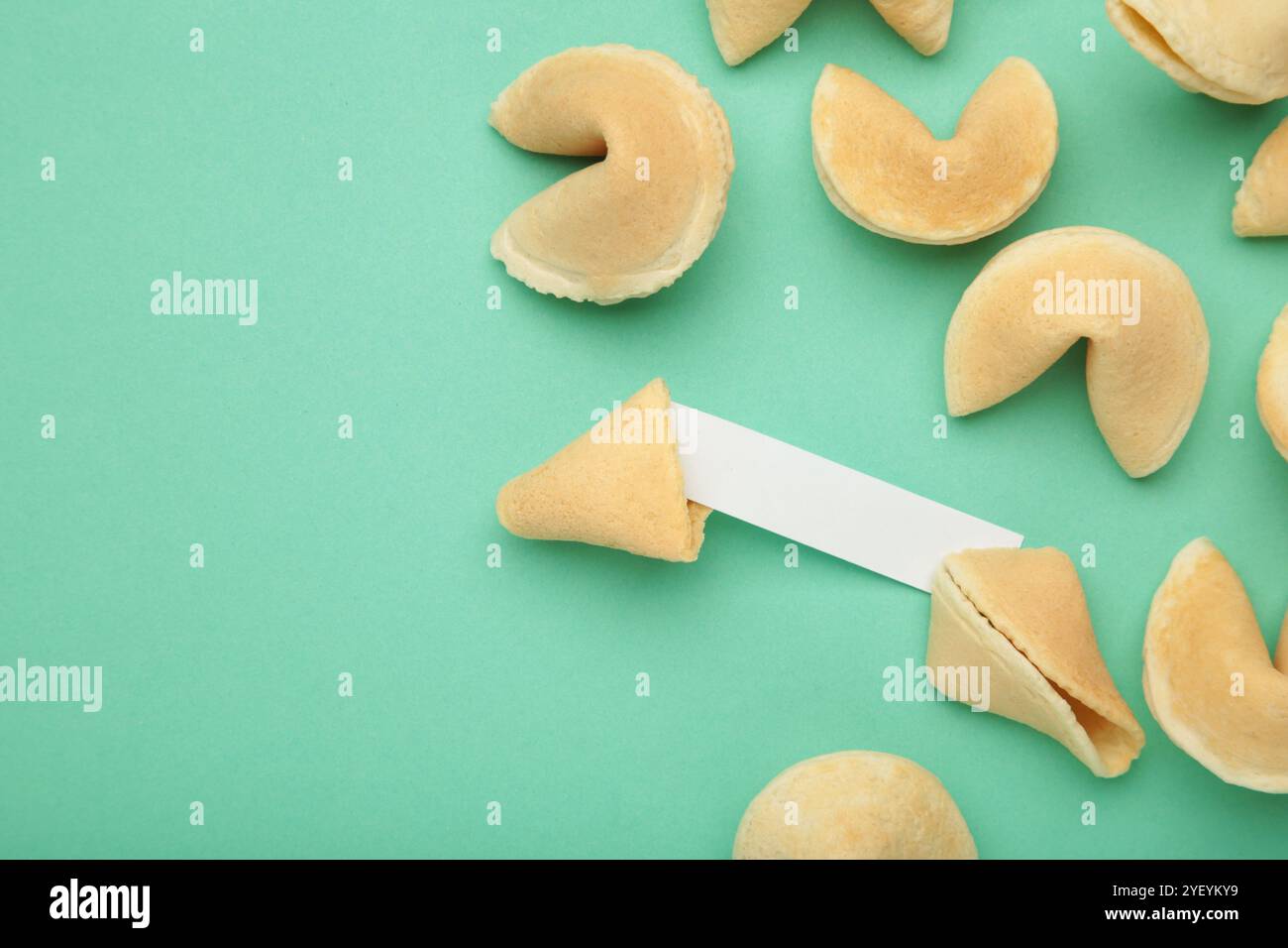 Tasty fortune cookies and paper with prediction on mint background ...
